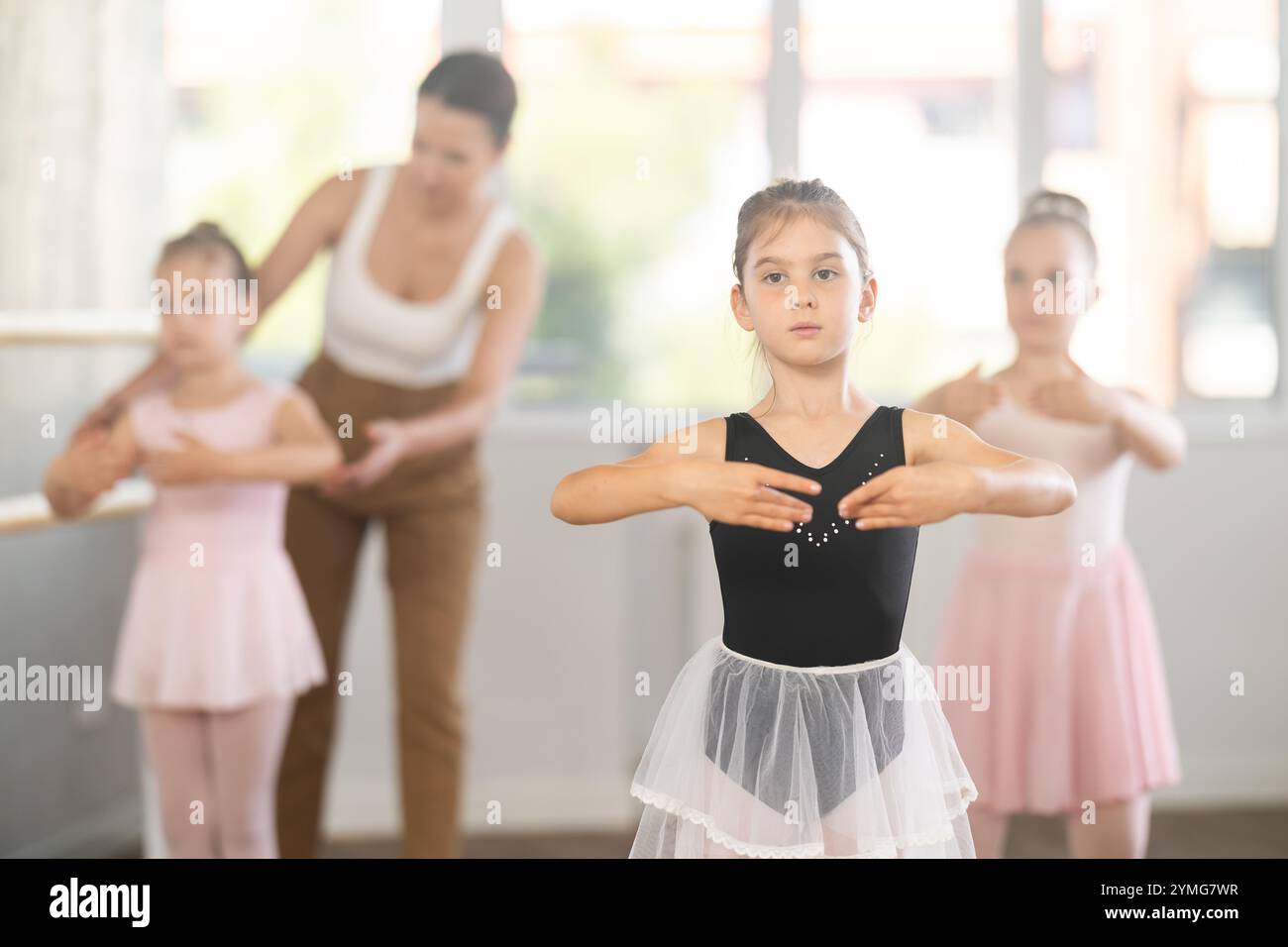 Girls in ballet class perform first position with correction of female ...