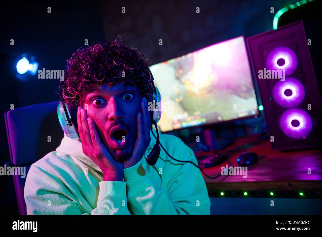 Photo of cute young guy scared amazed reaction play gamer computer ...