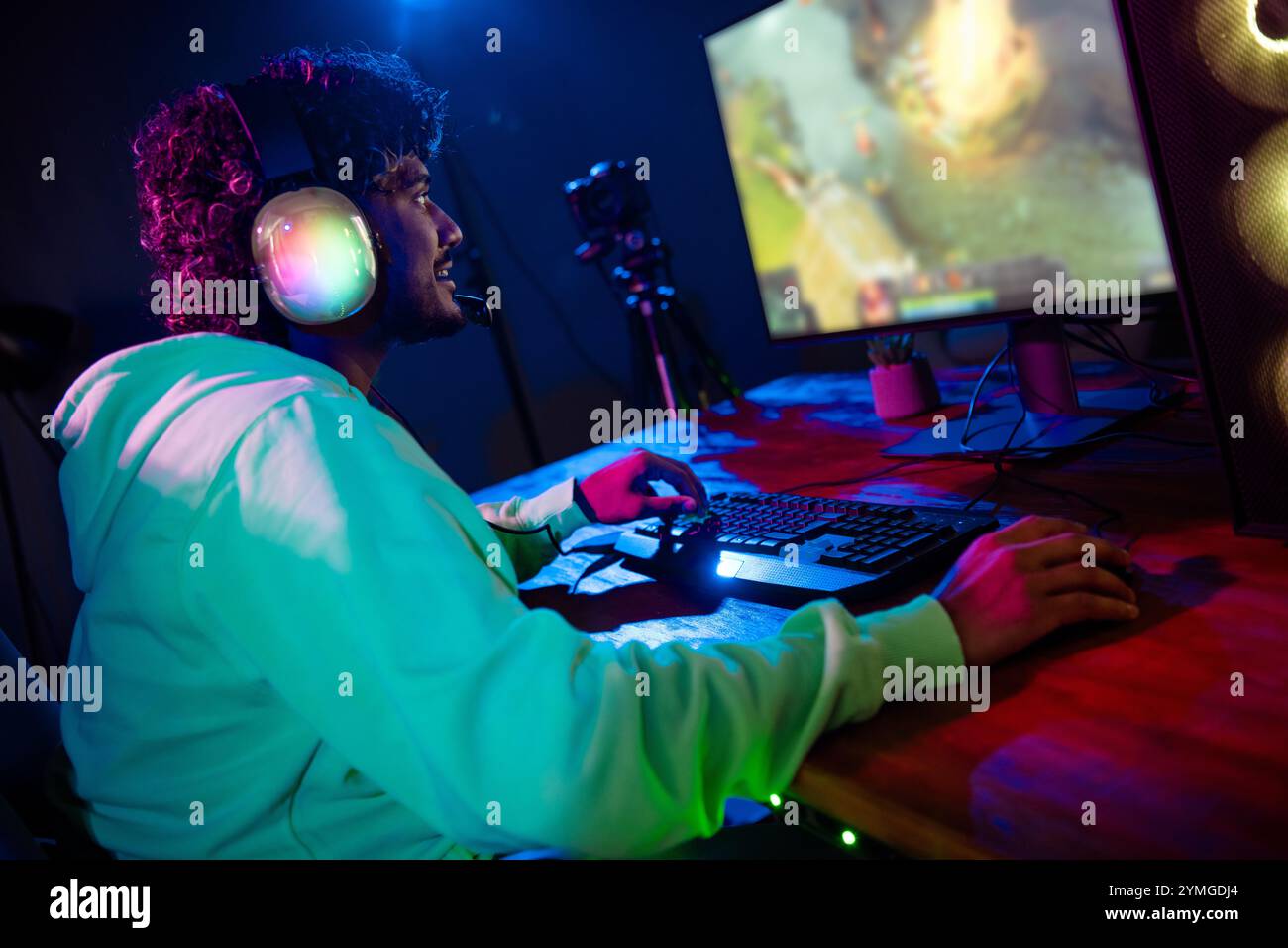 Photo of cute young guy big monitor play gamer computer purple blue ...