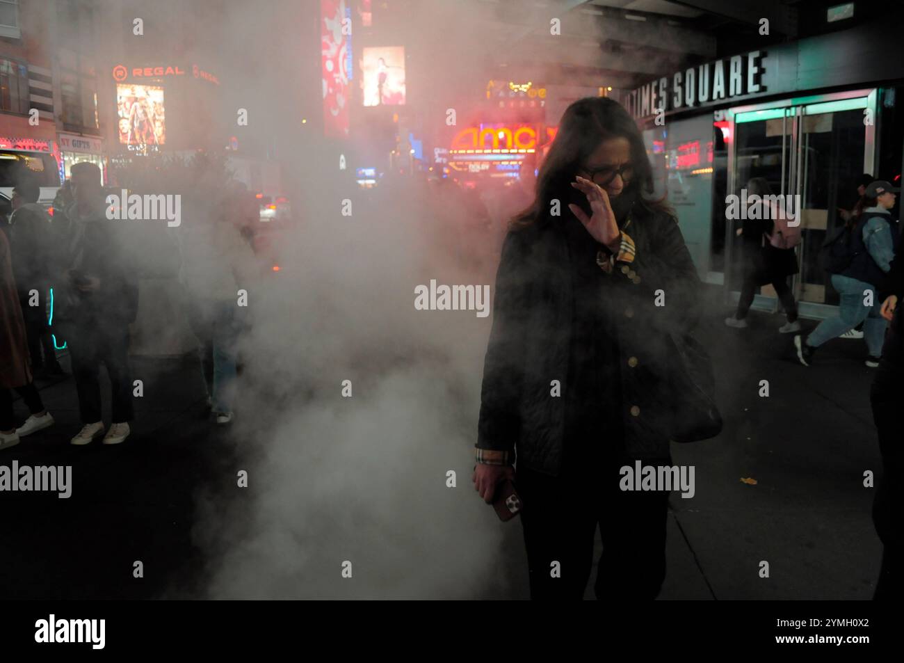 People walk past steam coming out from the ground on the street in ...