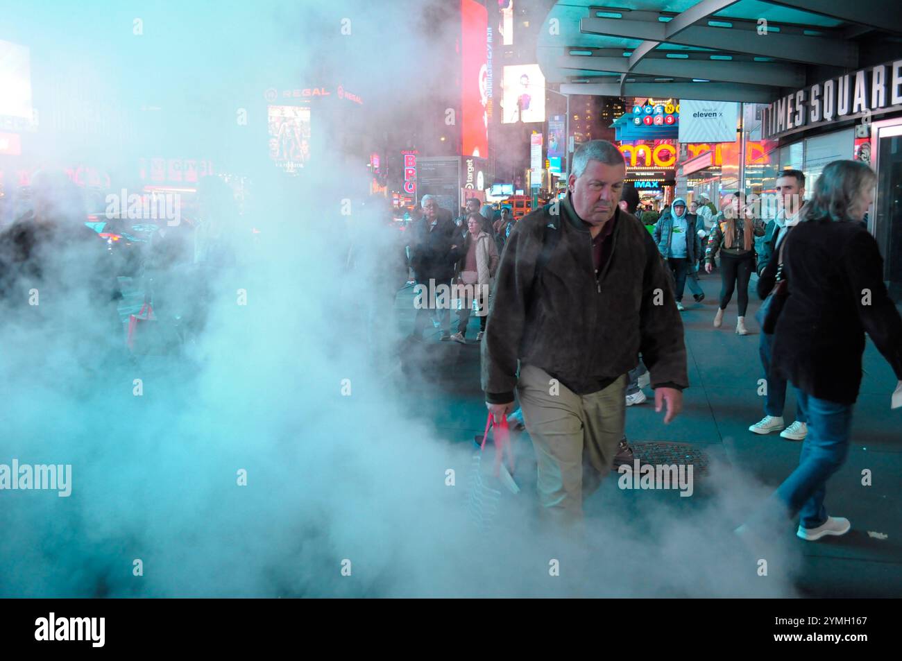 People walk past steam coming out from the ground on the street in ...
