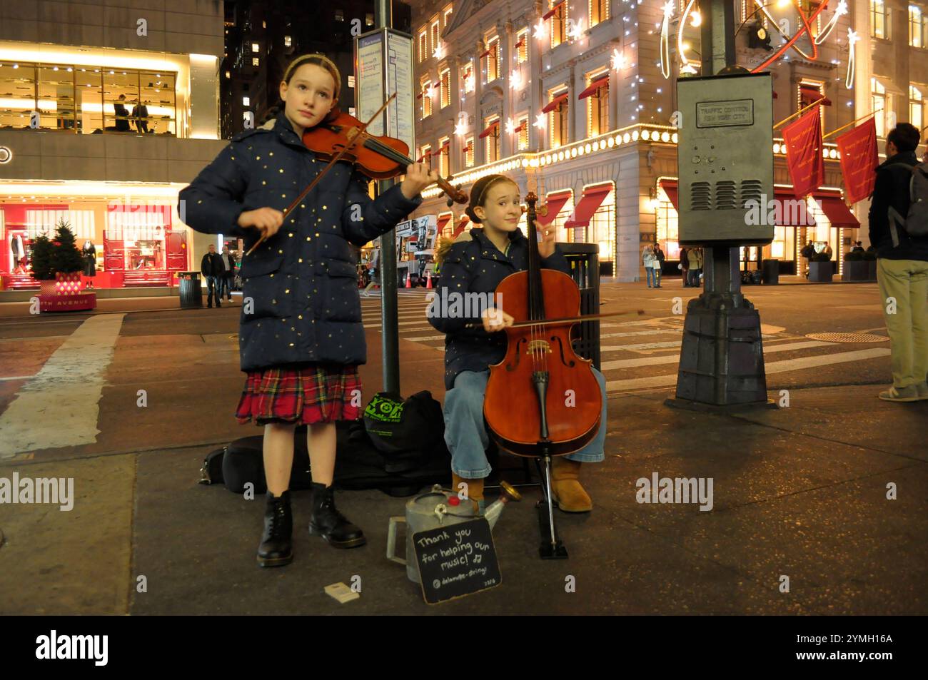 Children play music using string instruments on Fifth Avenue in ...