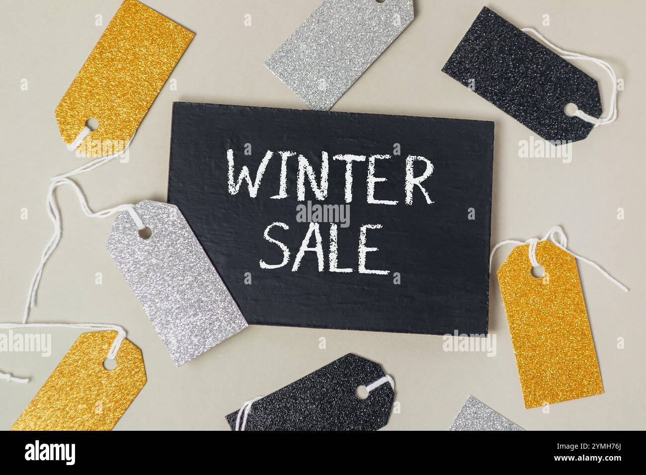 Black sign with the word Winter Sale written on it. There are many tags ...