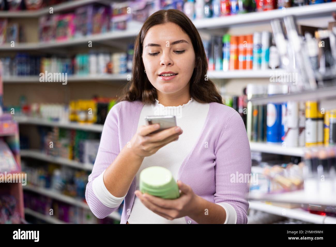 Female shopper scanning a QR code using a mobile phone in cosmetics ...
