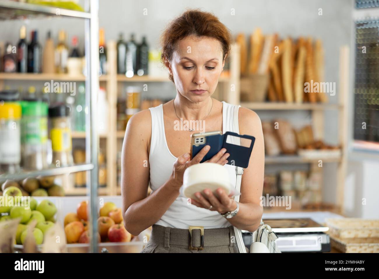 Female shopper scans QR code on cheese label using smartphone. Checking ...