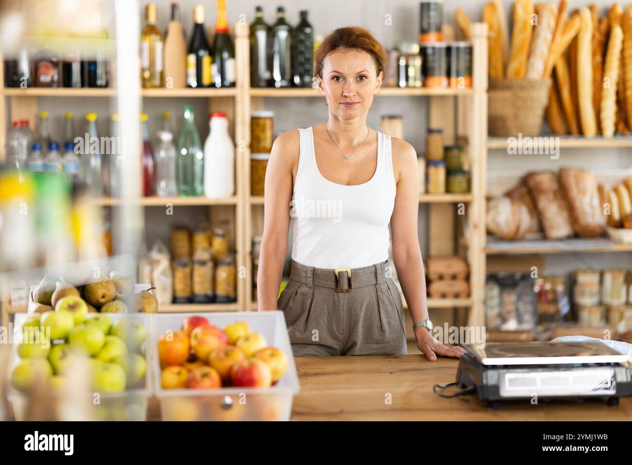 Adult female seller at counter in grocery store Stock Photo - Alamy
