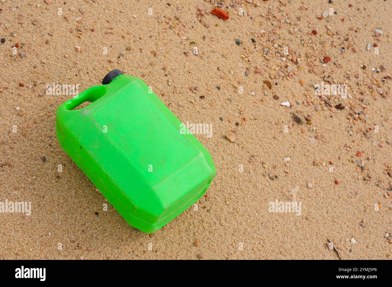 Green plastic container on sandy beach, highlighting environmental ...