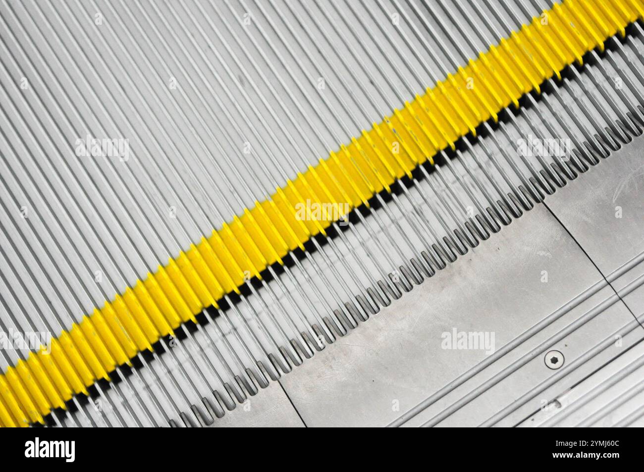 Modern escalator with yellow safety marks and metallic steps close-up ...