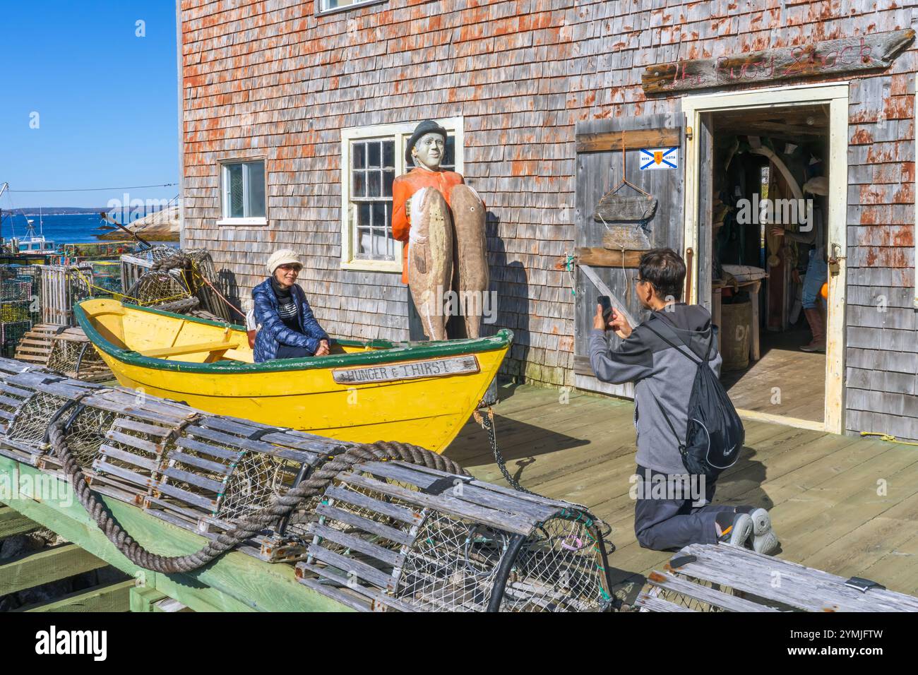 Tourist posing for photos in front of an antique shop in Peggy's Cove ...