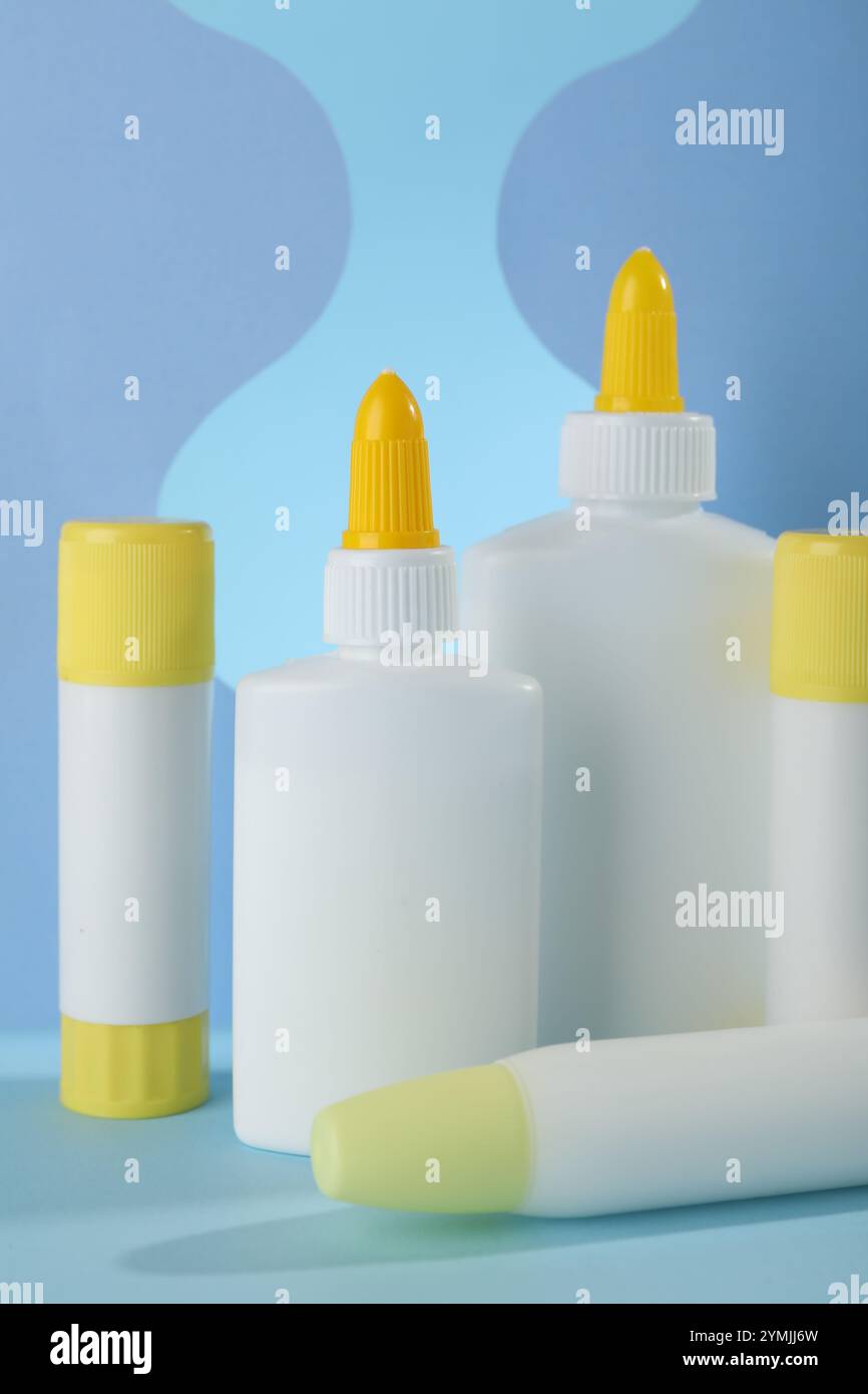 Different types of glue and paper cutouts on light blue background ...