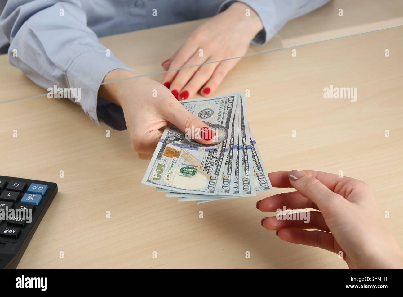 Cashier giving dollar banknotes to client at table in money exchange ...