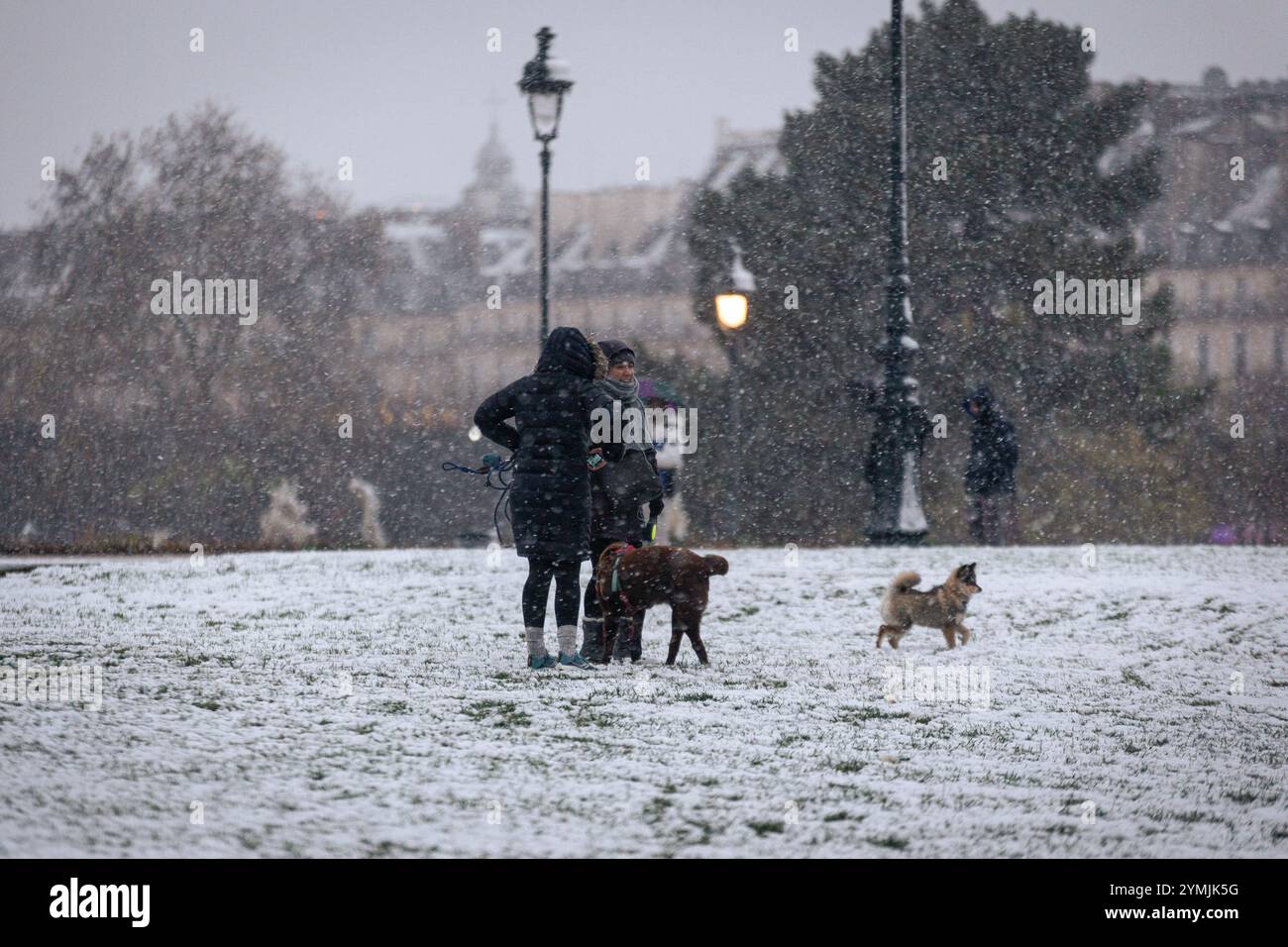 Two people walk their dogs at the Tuilleries Garden during the snowfall ...