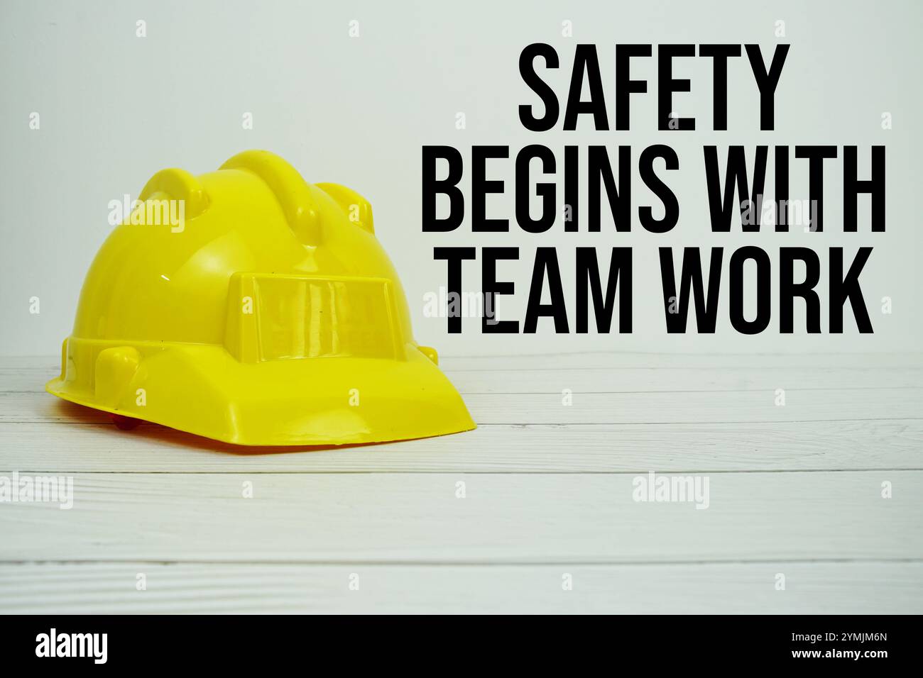 Safety Begins With Team Work text on blackboard with safety helmet on ...