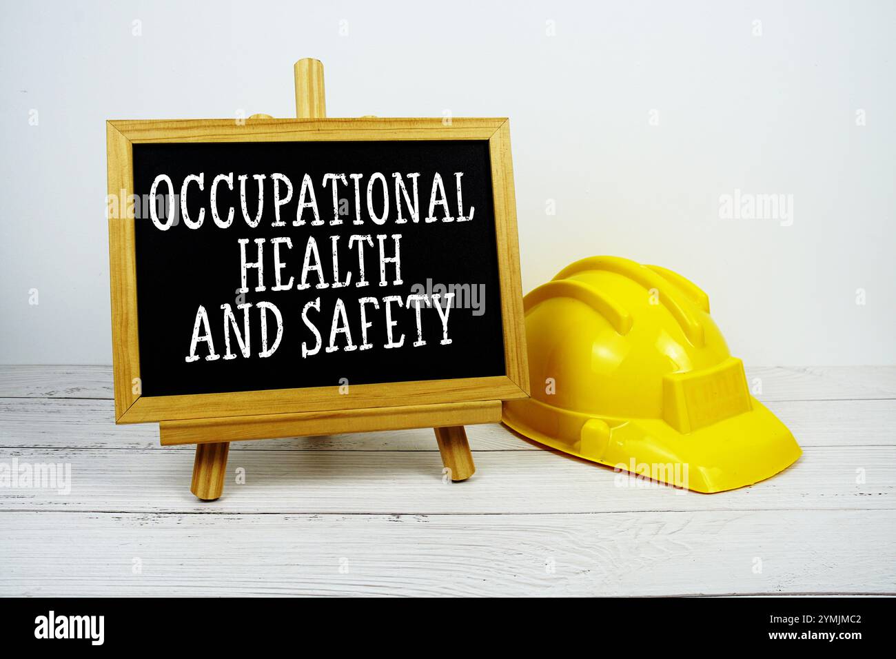 Occupational Health And Safety text on blackboard with safety helmet on ...