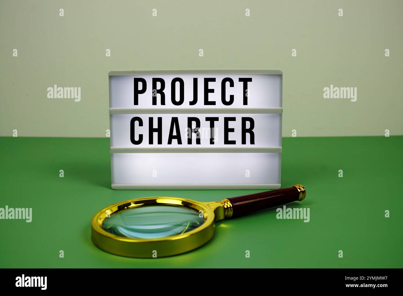 Project Charter text on LED lightbox with magnifying glass on green ...