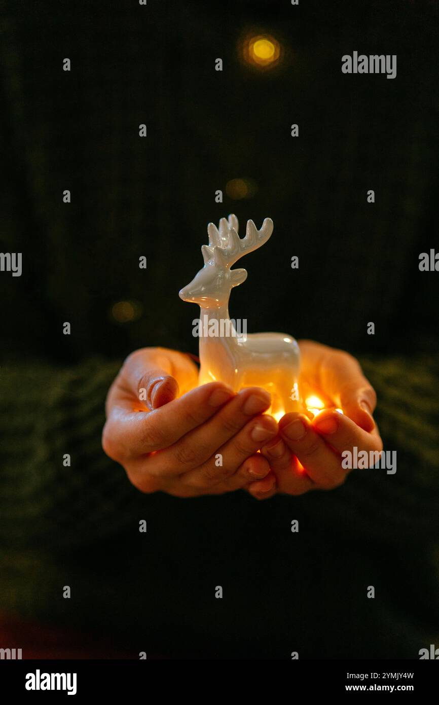 Warm festive Christmas image of hands holding deer ornament. Ceramic ...