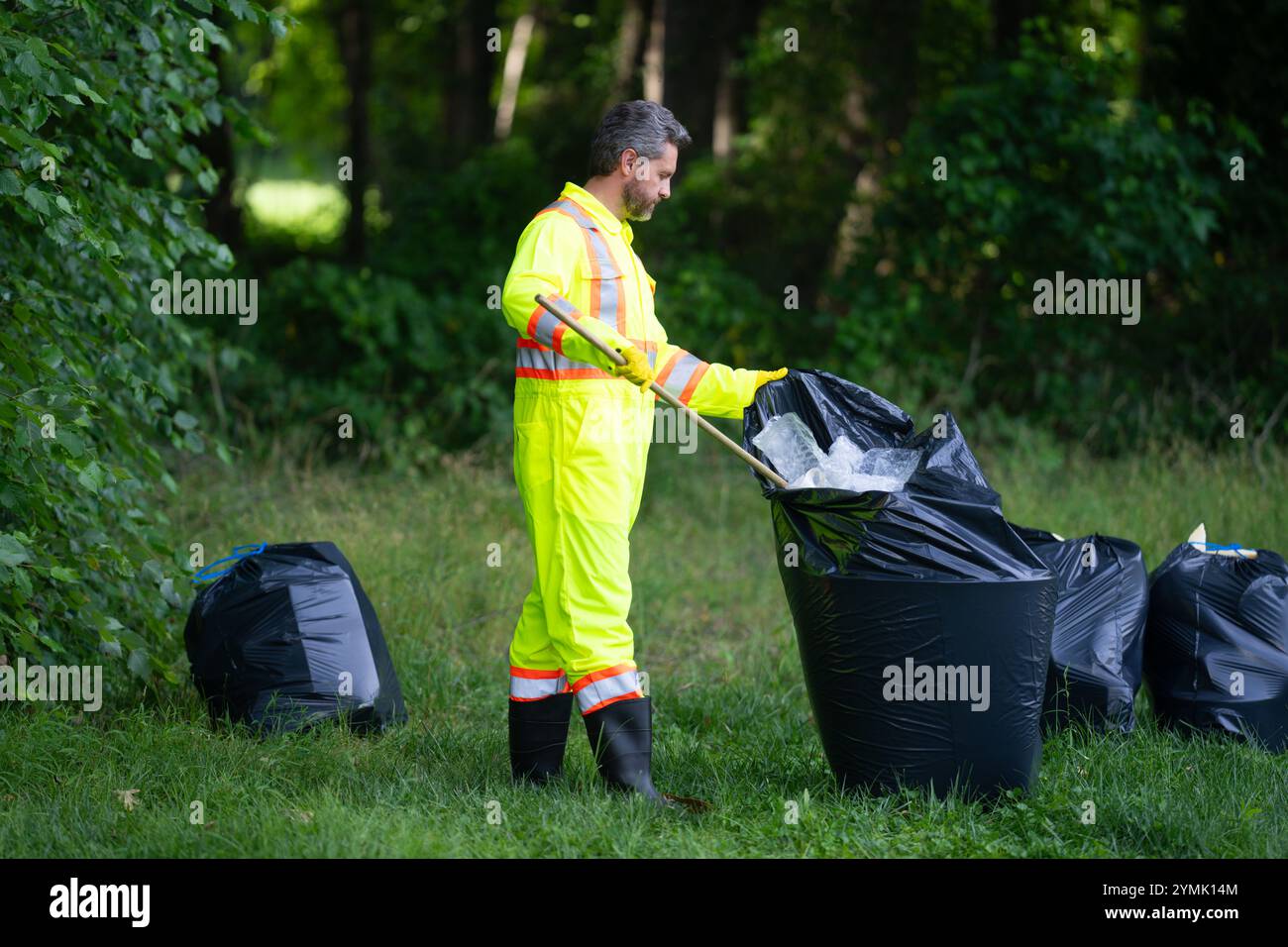Environment plastic pollution. Volunteer collecting trash in the forest and holding a garbage ...