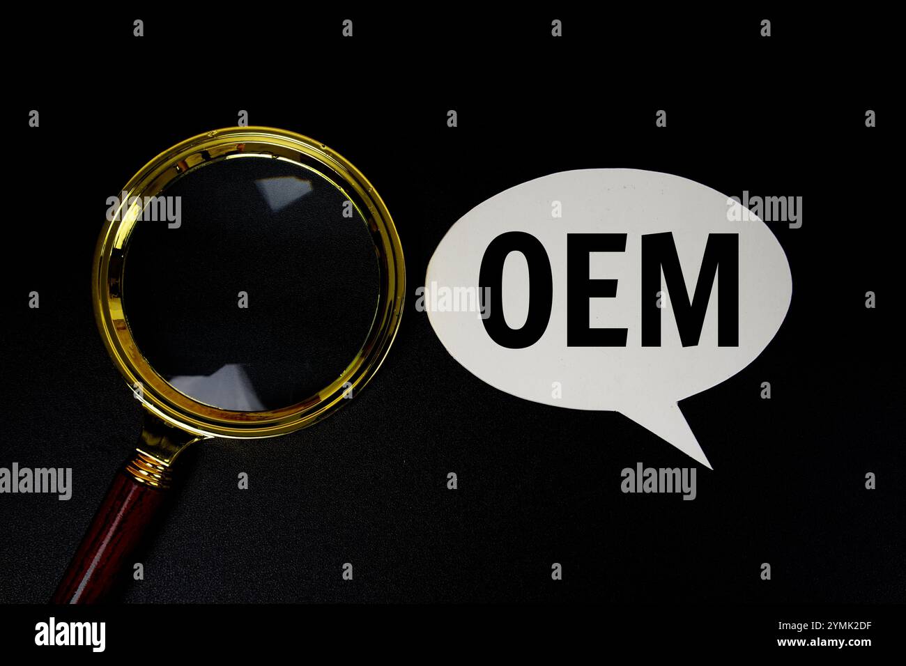 OEM text on speech bluble with magnifying glass top view on black ...