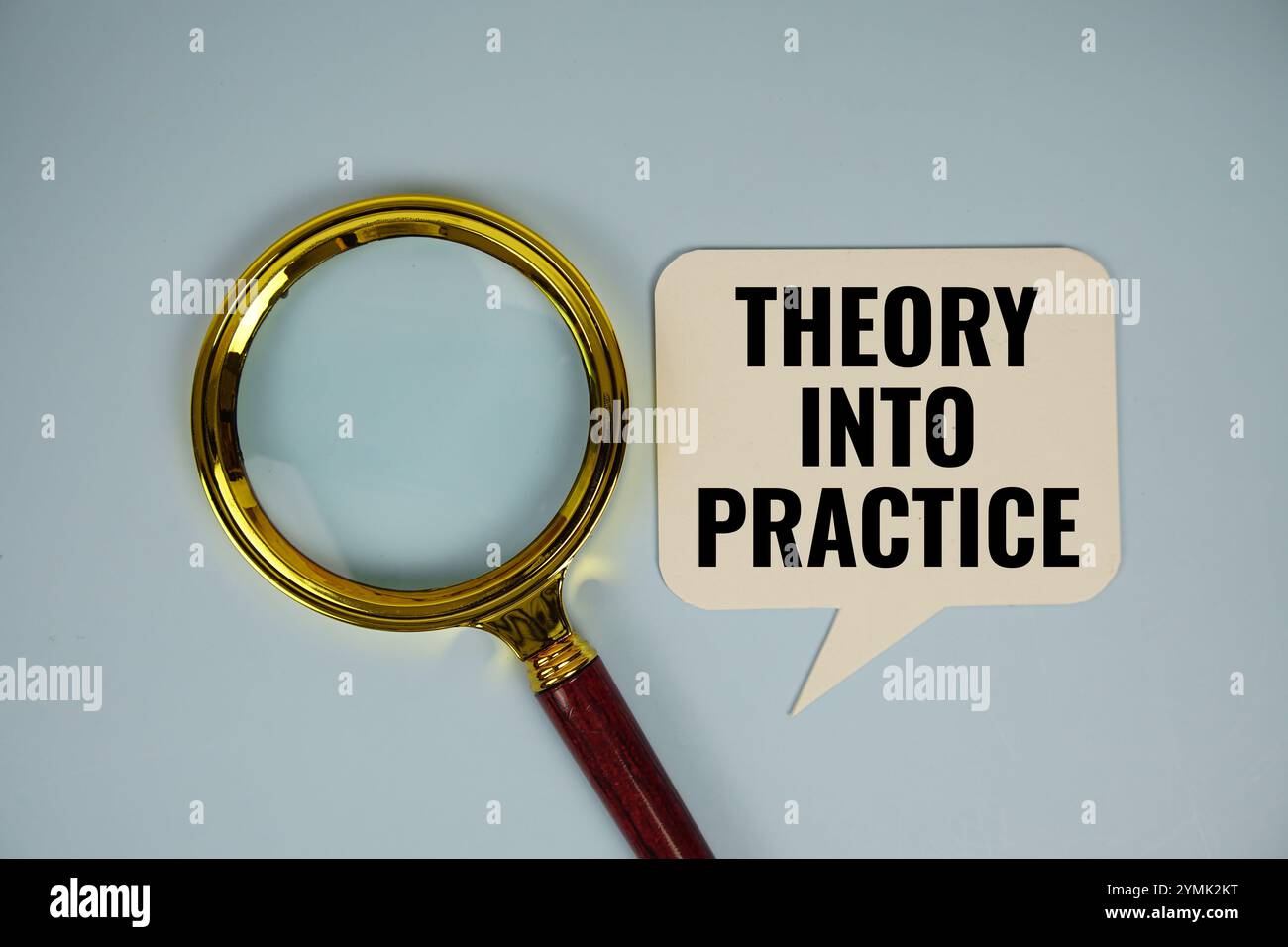 Theory into Practice text on speech bubble with magnifying glass top view on blue background ...
