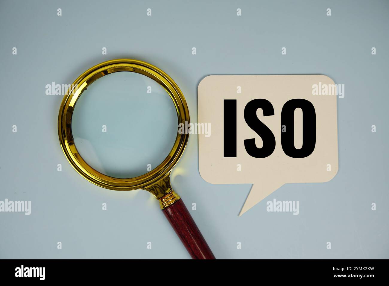 ISO text on speech bluble with magnifying glass top view on blue ...