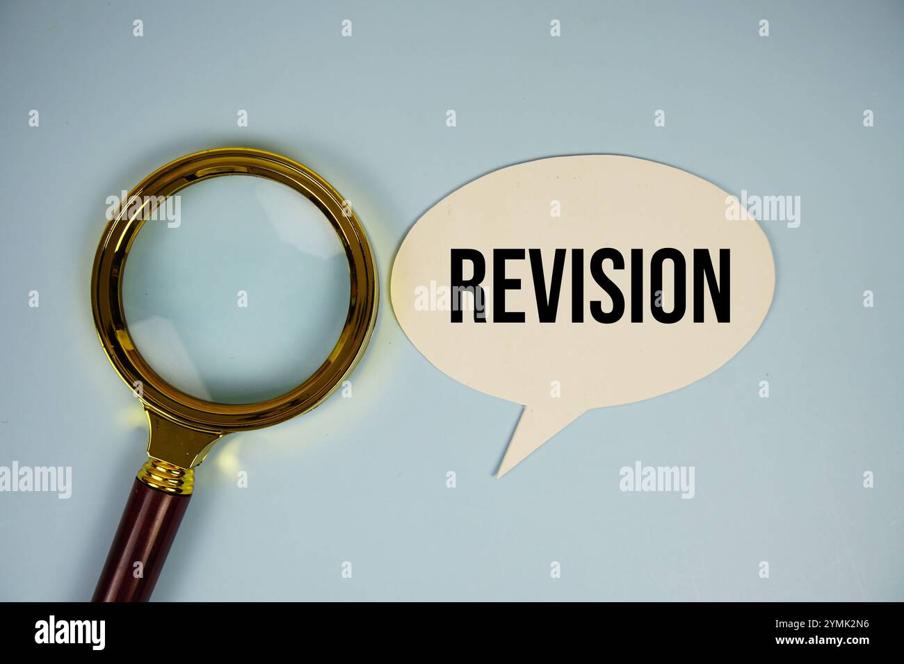 Revision text on speech bluble with magnifying glass top view on blue ...