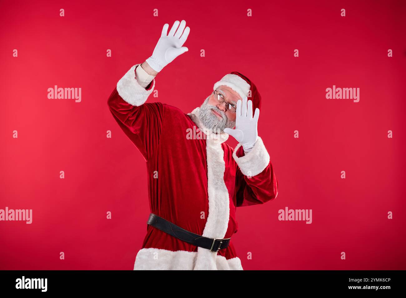 Santa Claus wearing traditional red suit and white gloves is waving ...