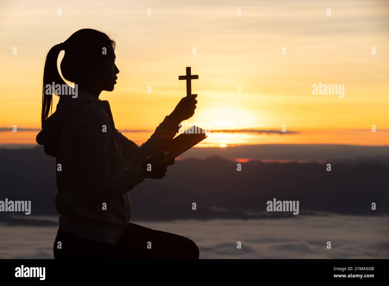 Silhouette of a woman praying on a mountain at sunrise. Young woman ...