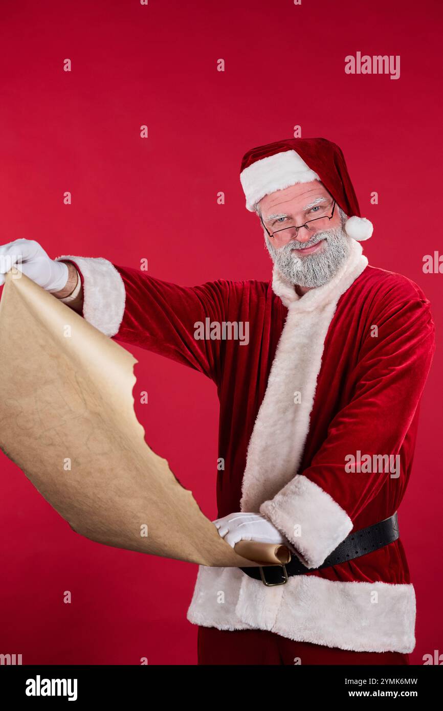 Santa Claus wearing traditional red suit and hat holding a long scroll ...