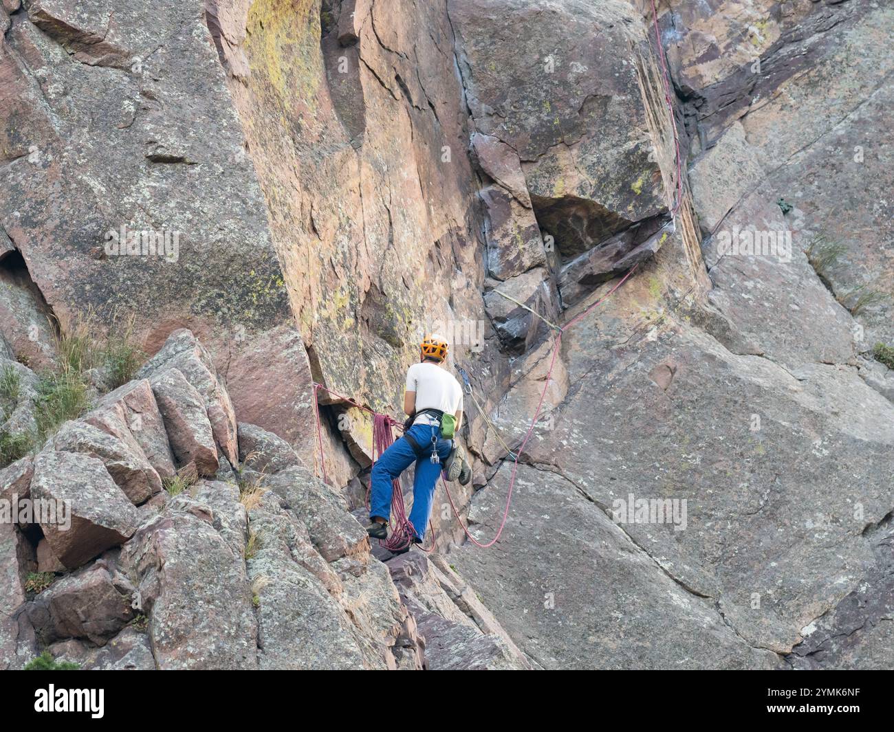 Solo male rock climber belaying for a fellow climber not pictured on ...