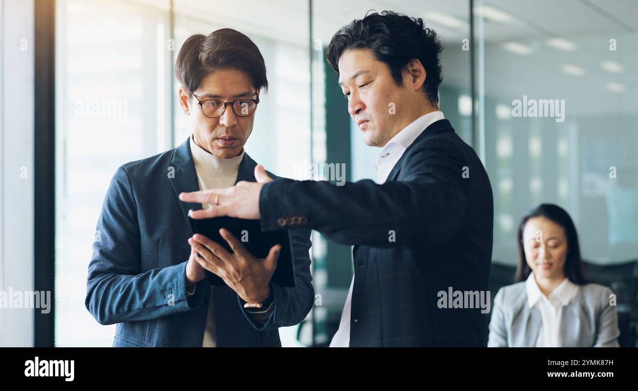 Tablet, teamwork and review with business people in Japanese office for planning, feedback and ...