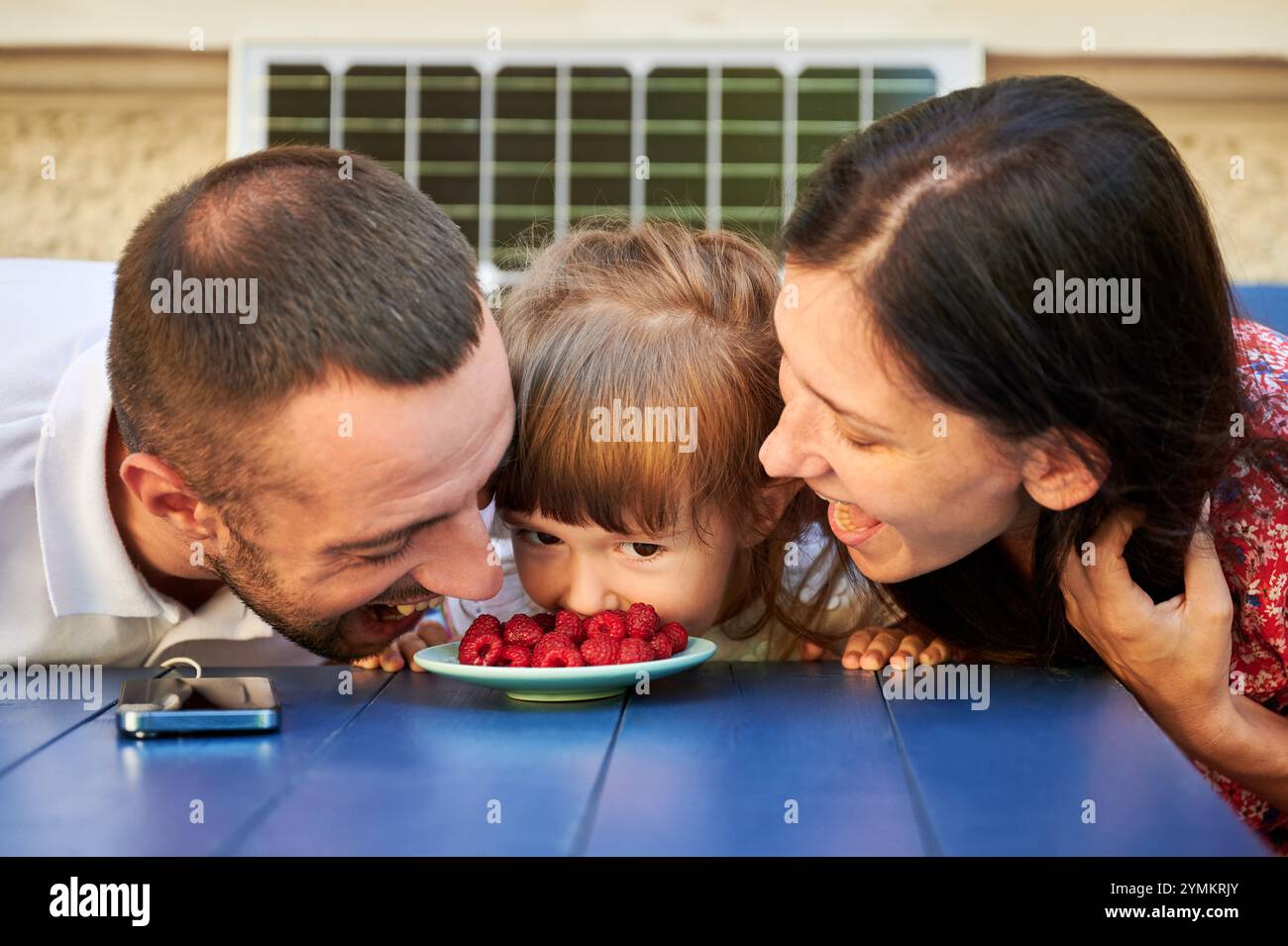Lovely moment of family eating berries without hands. Little girl ...