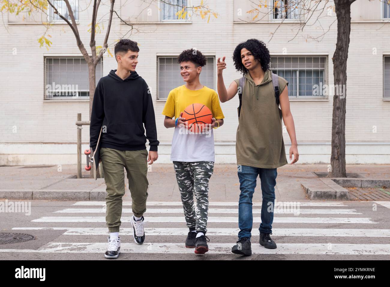 three diverse friends talking while crossing road Stock Photo - Alamy