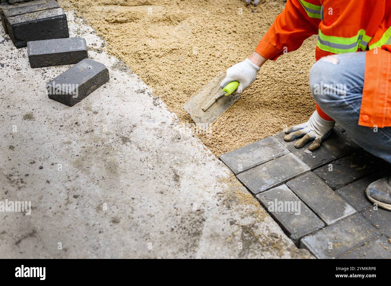 Worker laying brick pavers on the sidewalk. Road paving and repairing ...