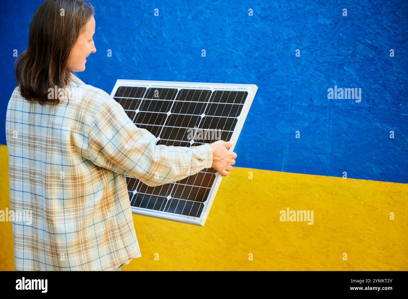 Woman holding solar panel for charging. Smiling female wears plaid ...