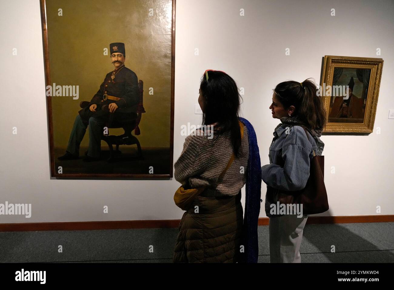 Two women look at a portrait of late Nasser-e-Din Shah, a king of Qajar ...