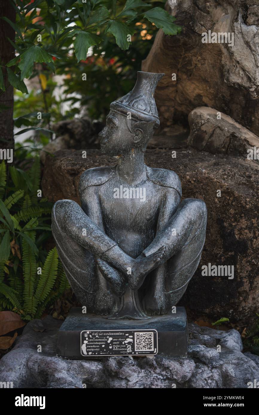 A bronze sculpture depicts a seated figure with a distinctive posture ...