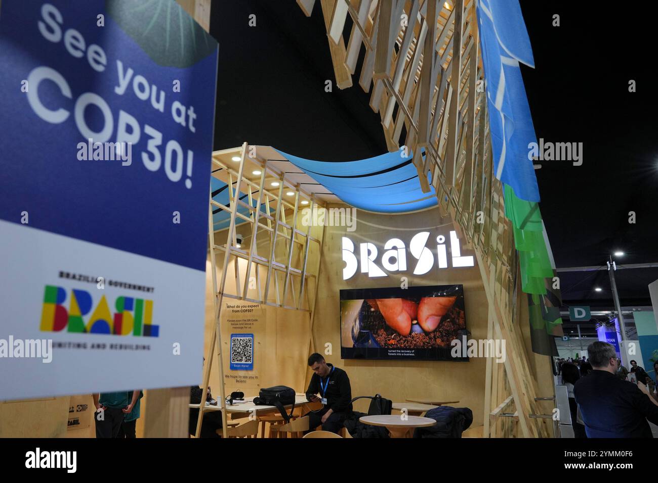 A person sits in the Brazil Pavilion that displays a sign that reads ...