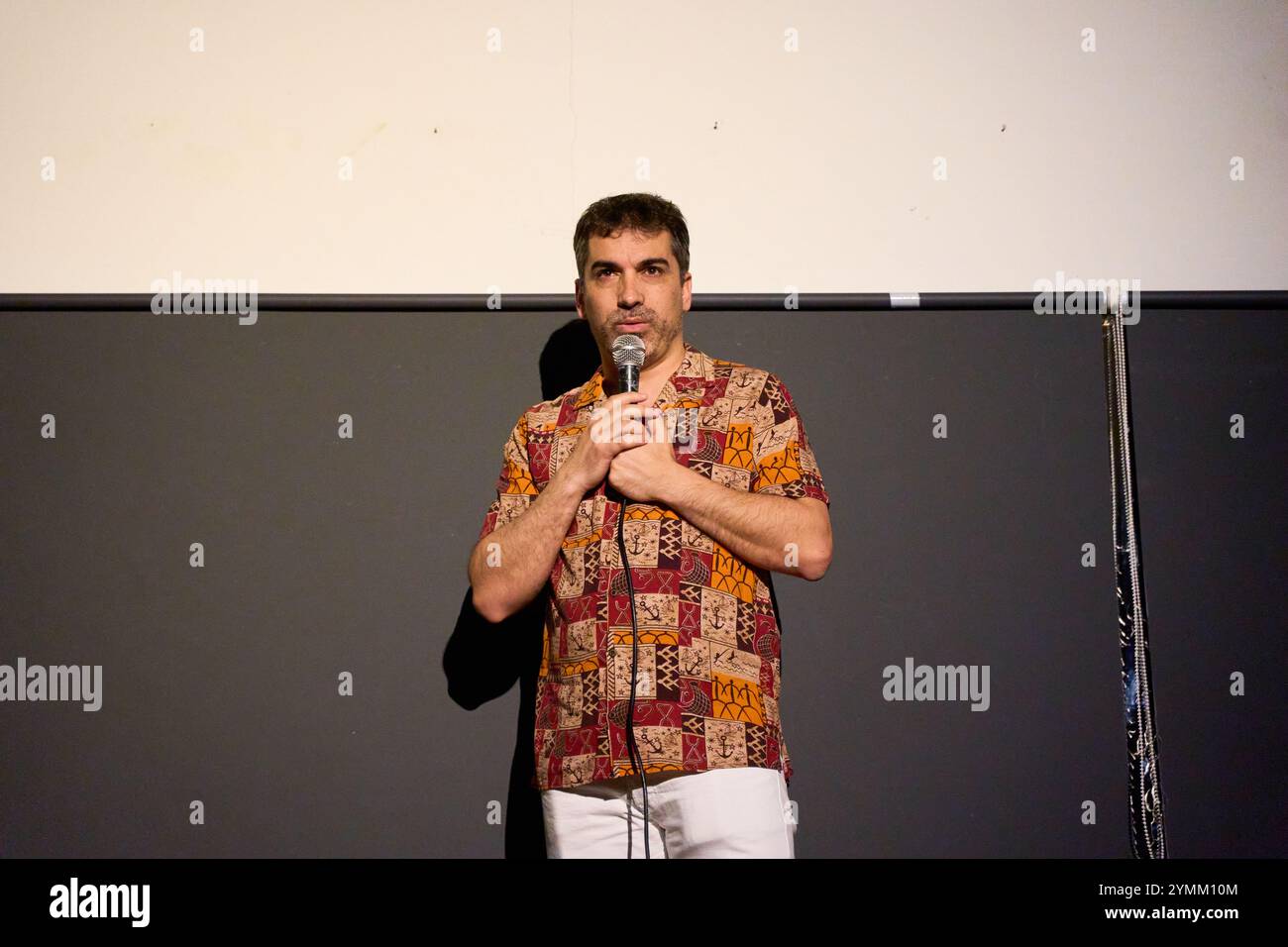 Male performer delivering a monologue on stage in a dimly lit theater ...