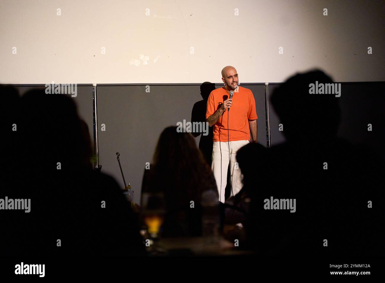 Male performer with shaved head delivering a monologue on stage in an ...