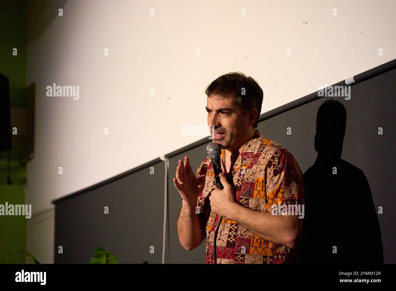 Male performer delivering a monologue on stage in a dimly lit theater ...