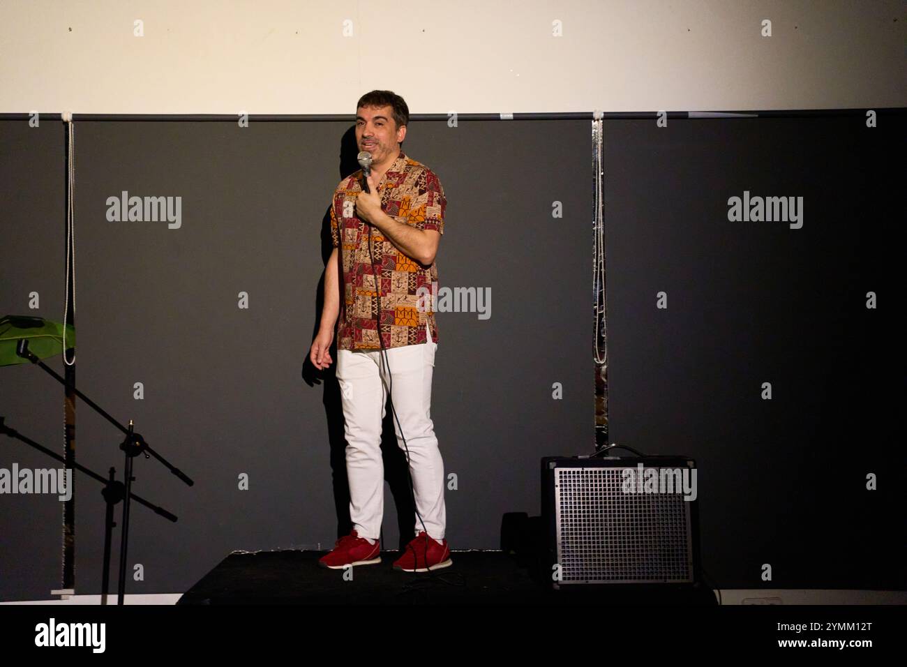 Male performer delivering a monologue on stage in a dimly lit theater ...