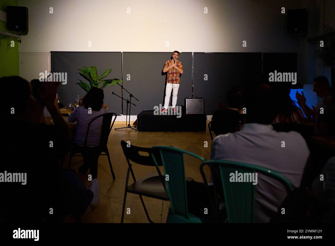 Male performer delivering a monologue on stage in a dimly lit theater ...