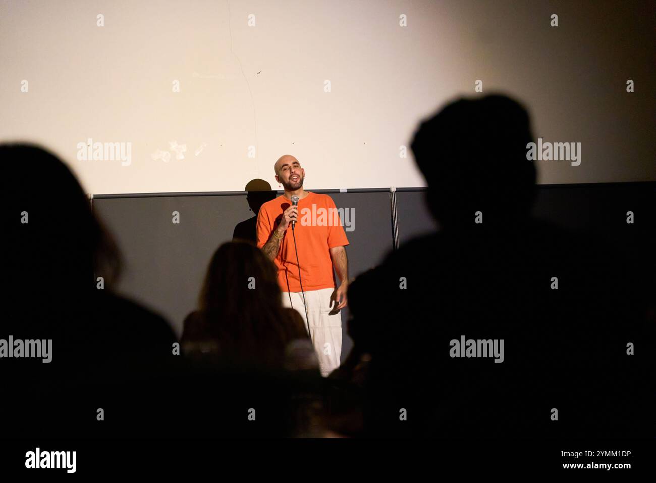 Male performer with shaved head delivering a monologue on stage in an ...