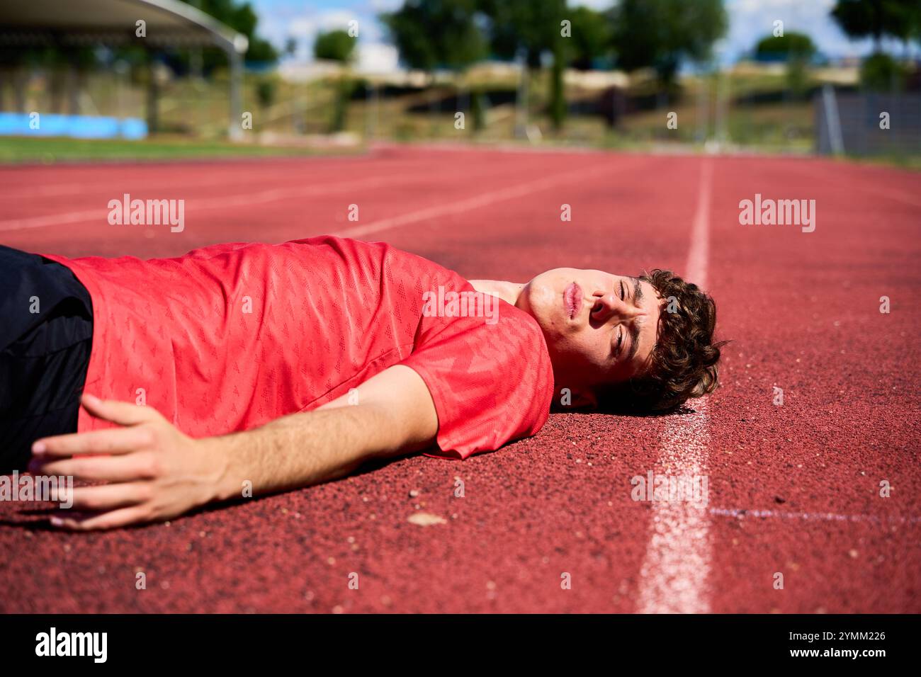 Exhausted young sprinter lying on the track after intense training ...