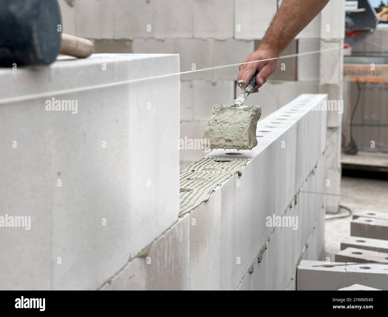 Construction worker building house walls with concrete sand lime bricks and thin bed adhesive ...