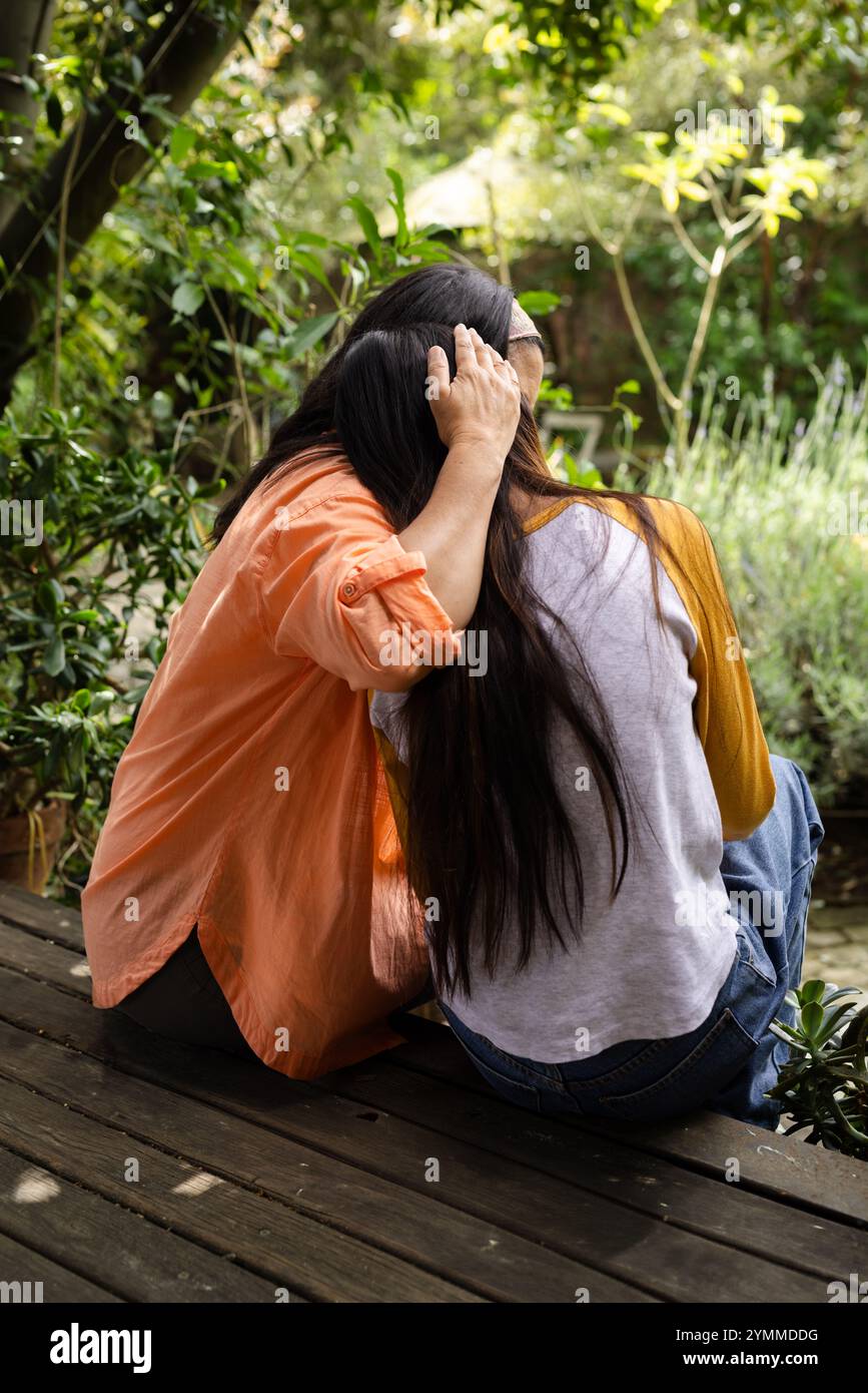 Grandmother and asian female teenager sharing heartfelt moment outdoors in lush garden. Family ...