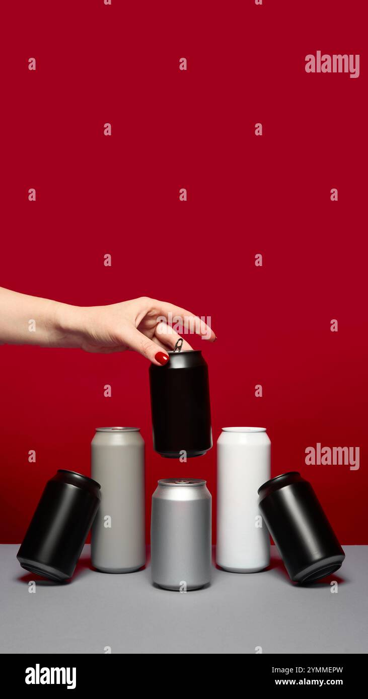 Female hand grabbing black aluminum can from row of cans in various ...