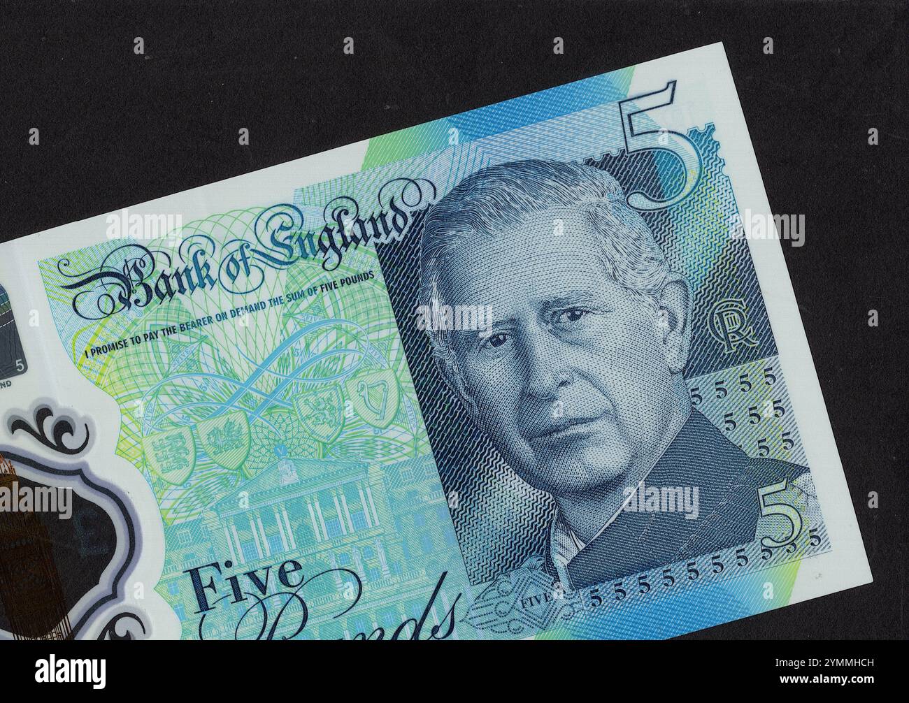 A King Charles III £5 banknote from the United Kingdom on a black ...