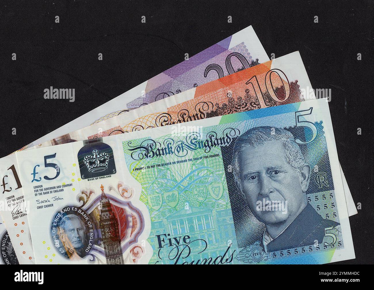 A King Charles III £5 banknote from the United Kingdom in a fan of ...