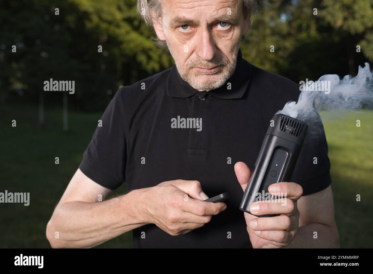 Older man uses two types of smoke machine generators on outdoor ...
